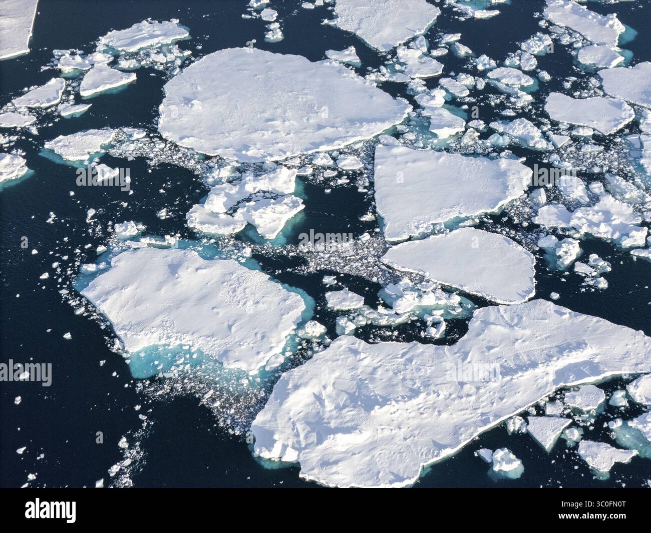 Aerial view of scattered ice floes juxtapose the dark, frigid waters ...