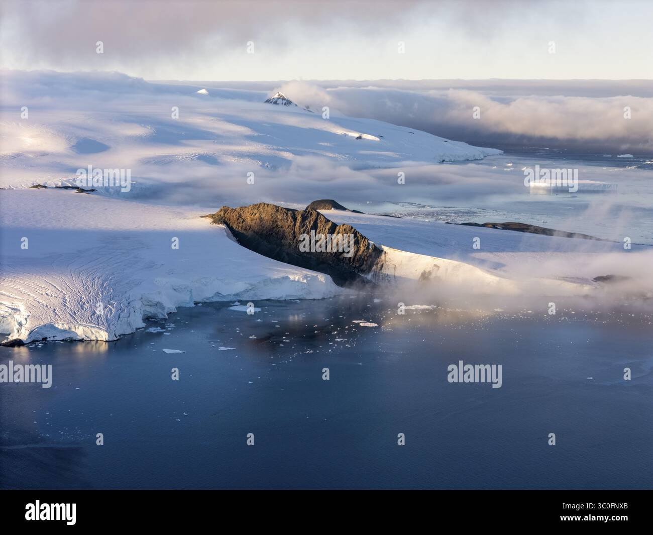 Aerial view of a rocky outcrop meets the icy expanse, shrouded in ...