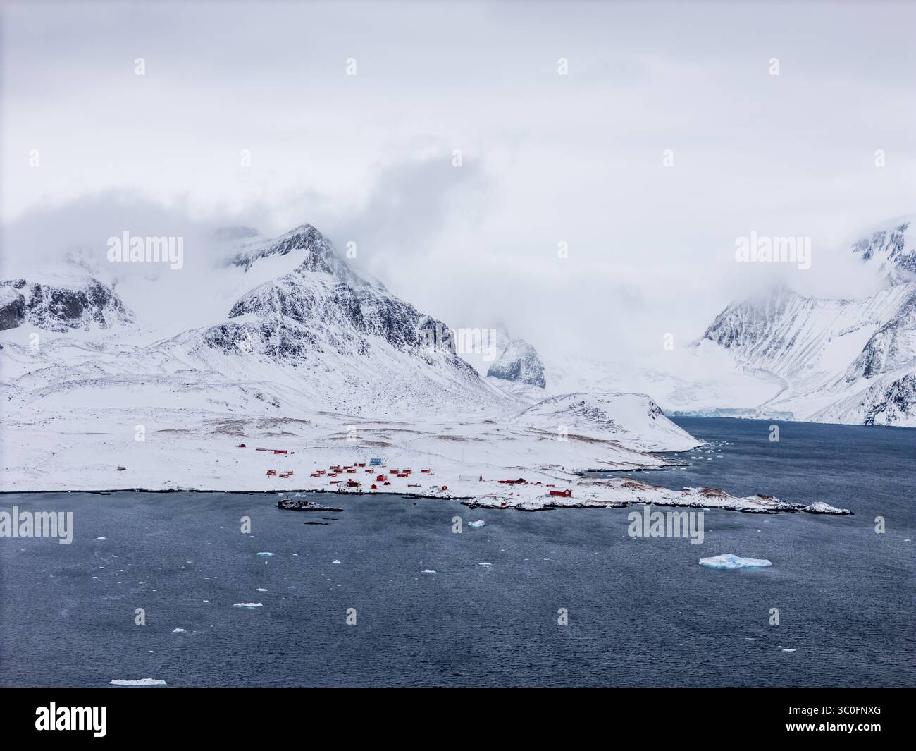 Aerial view of a research station nestled on the icy shores, stark ...