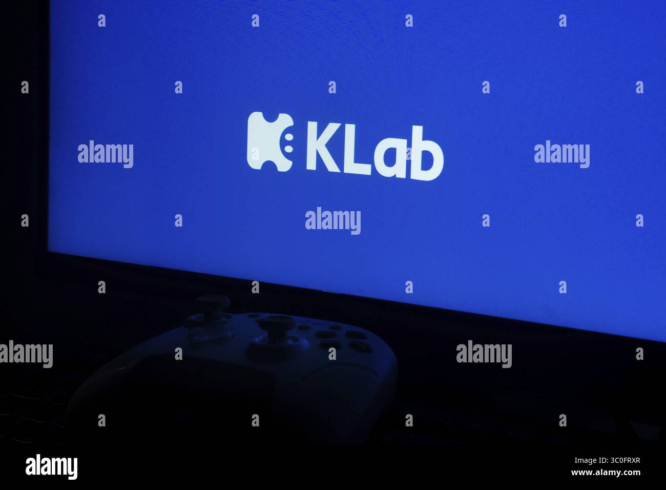 Screen showing KLab logo with a gaming controller positioned at the bottom Stock Photo - Alamy