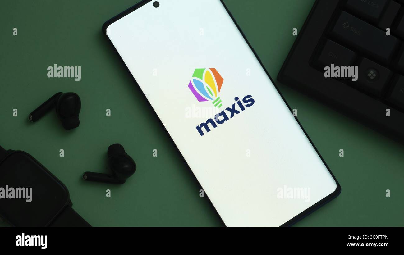 Smartphone displaying Maxis logo on green background with earbuds and a ...