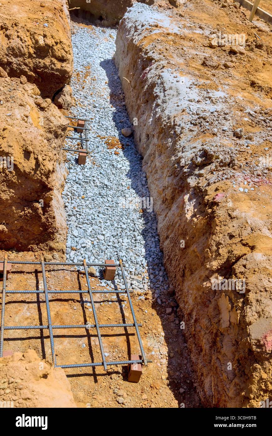 Excavated trench filled with gravel, steel reinforcement rebar ready ...