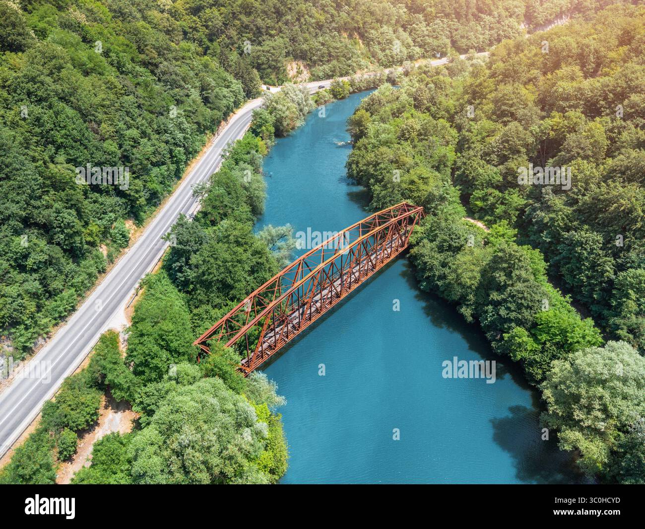 Aerial view of an old rusty metal bridge crossing a blue river near an ...