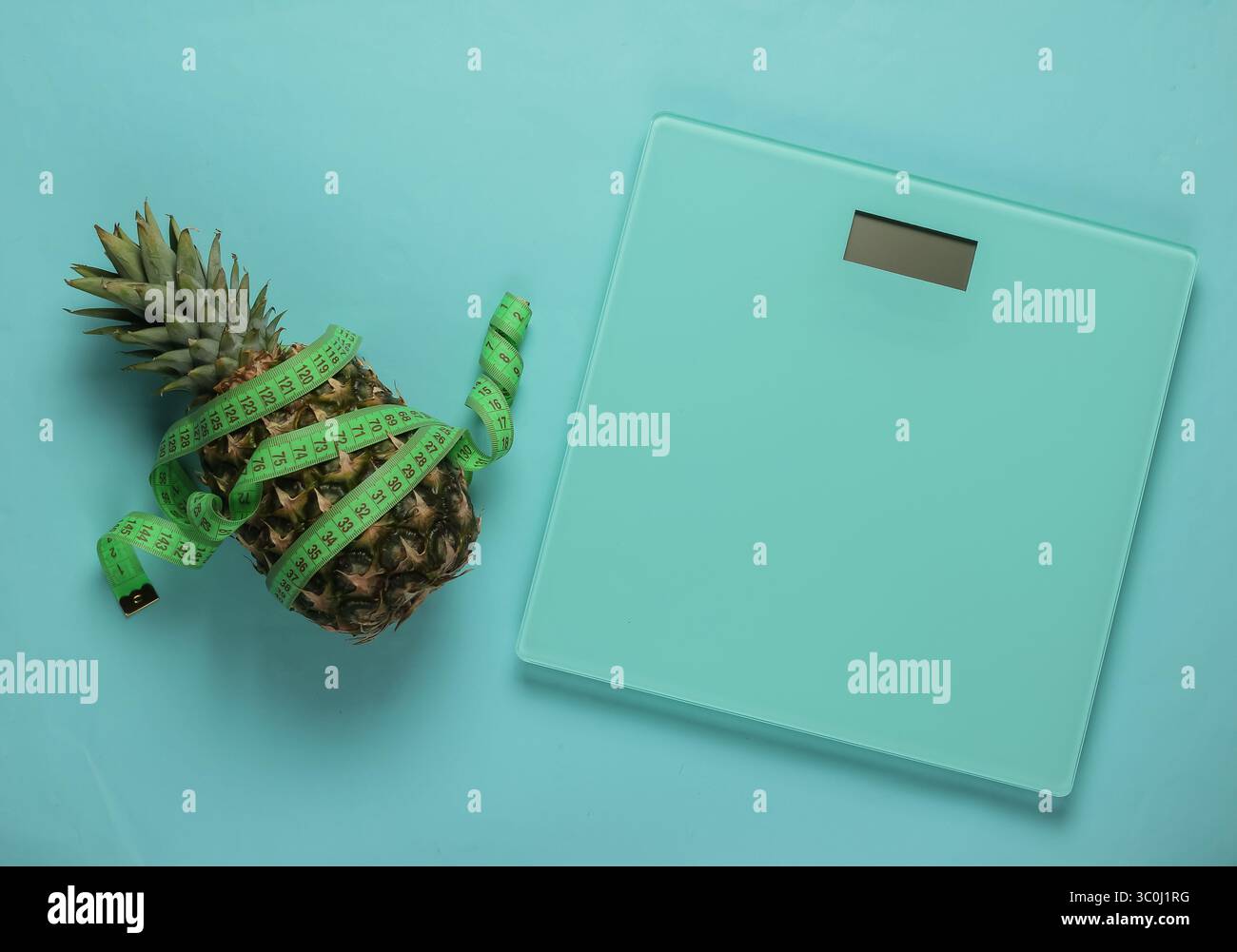 The concept of losing weight. Scales, pineapple wrapped with measuring ...