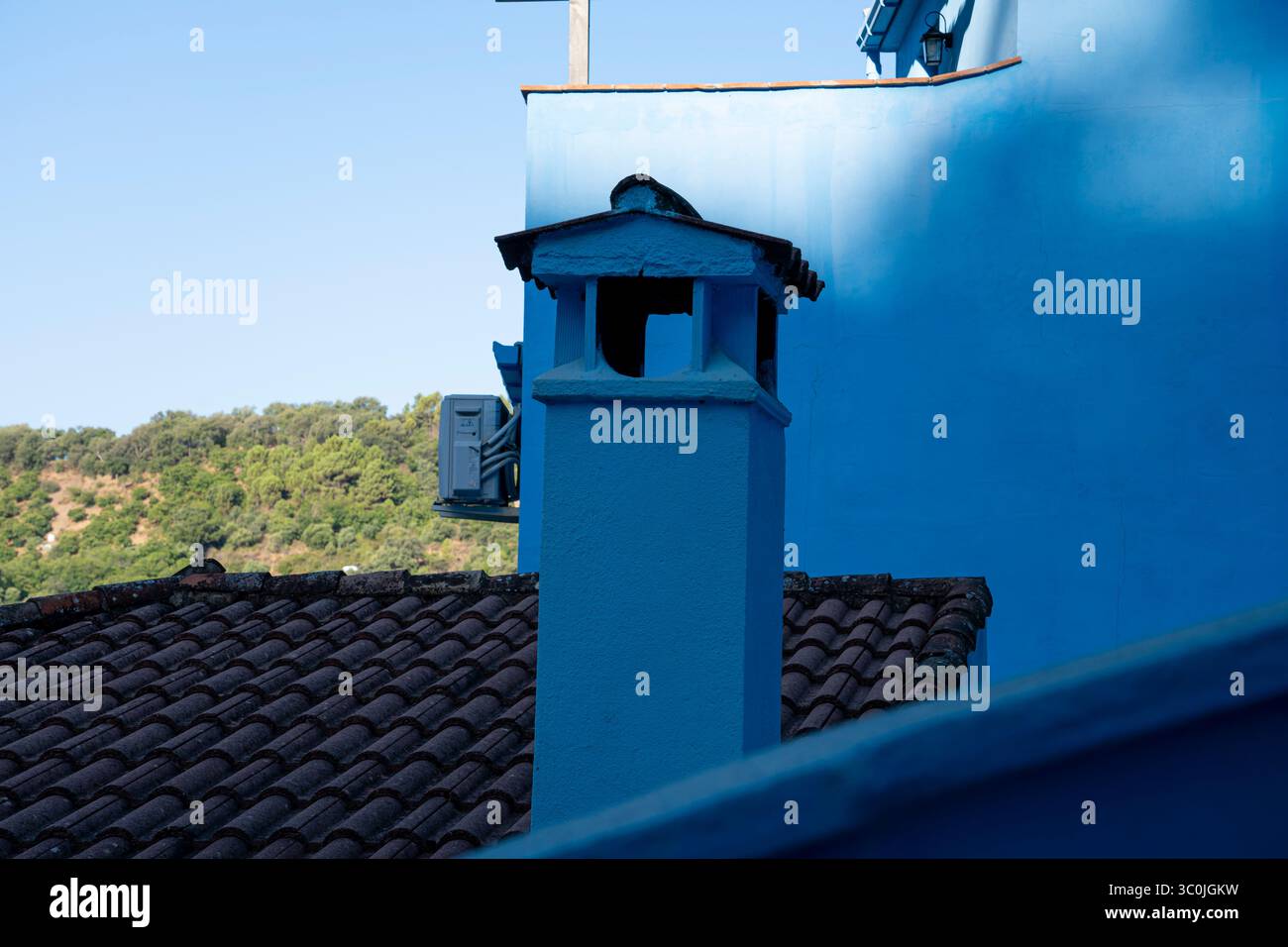 A striking blue chimney stands out against the tranquil backdrop of ...