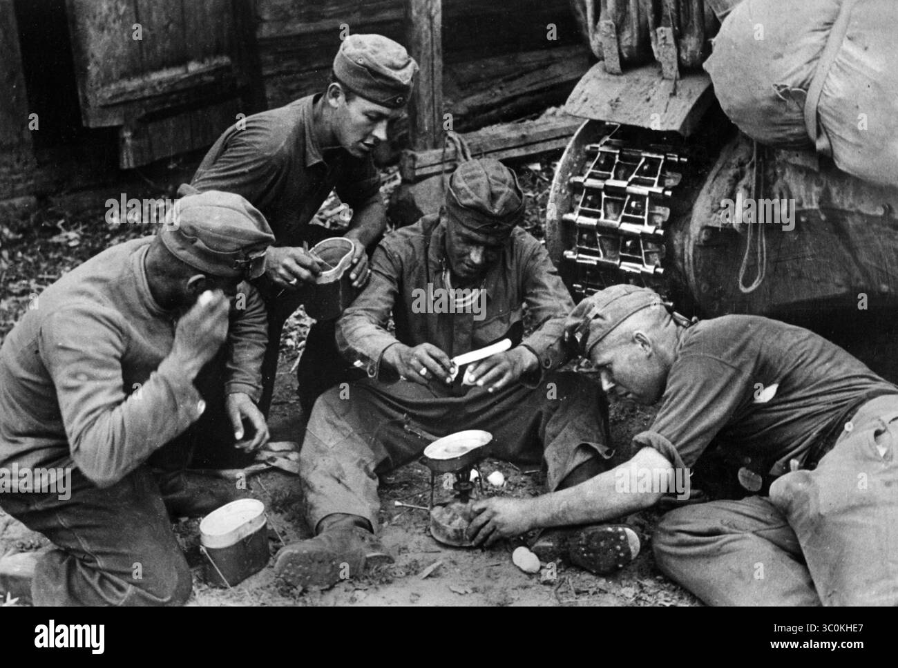 German army tankmen cook themselves fried eggs on a camping stove ...