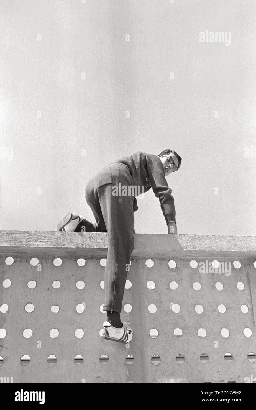 Italian sprinter Livio Berruti climbing a wall at the Rome Olympic ...