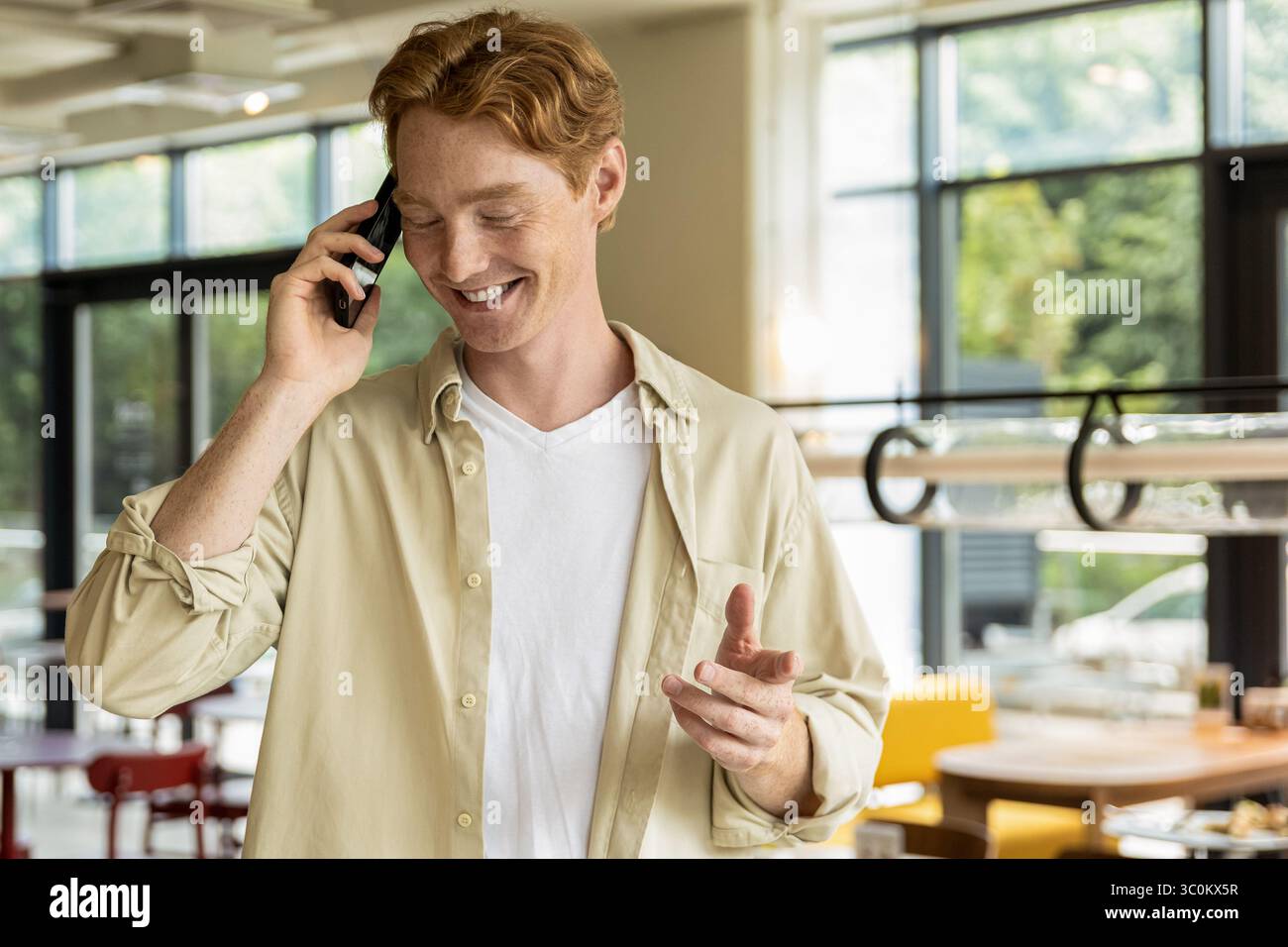 Ginger young man in cafe talking on the phone and looking enjoyed Stock ...
