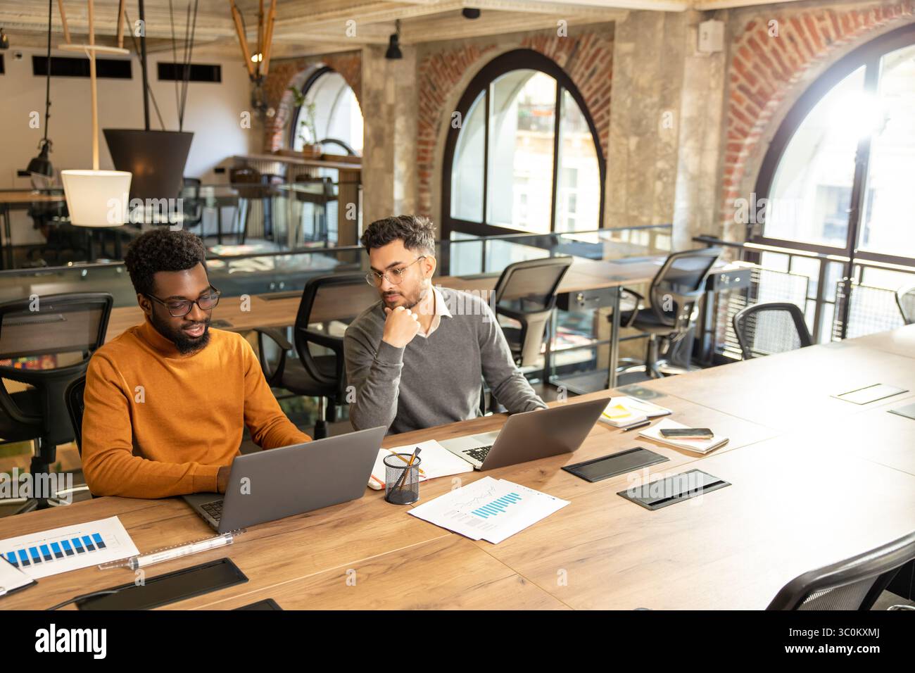Two young men working together in the office and looking involved Stock ...