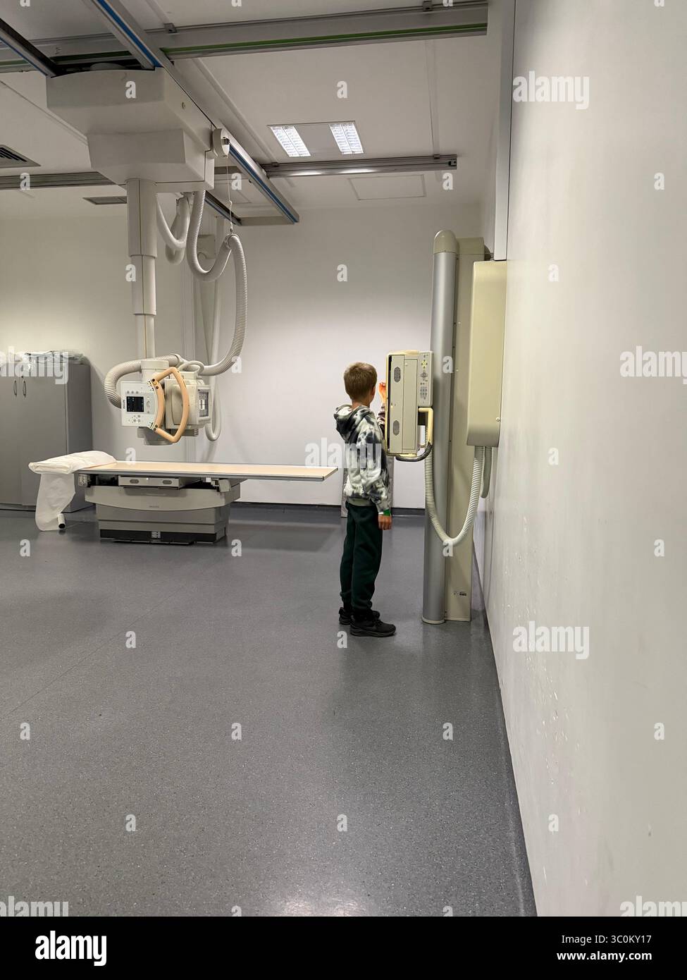 Child standing in X-ray room during radiography exam in medical ...