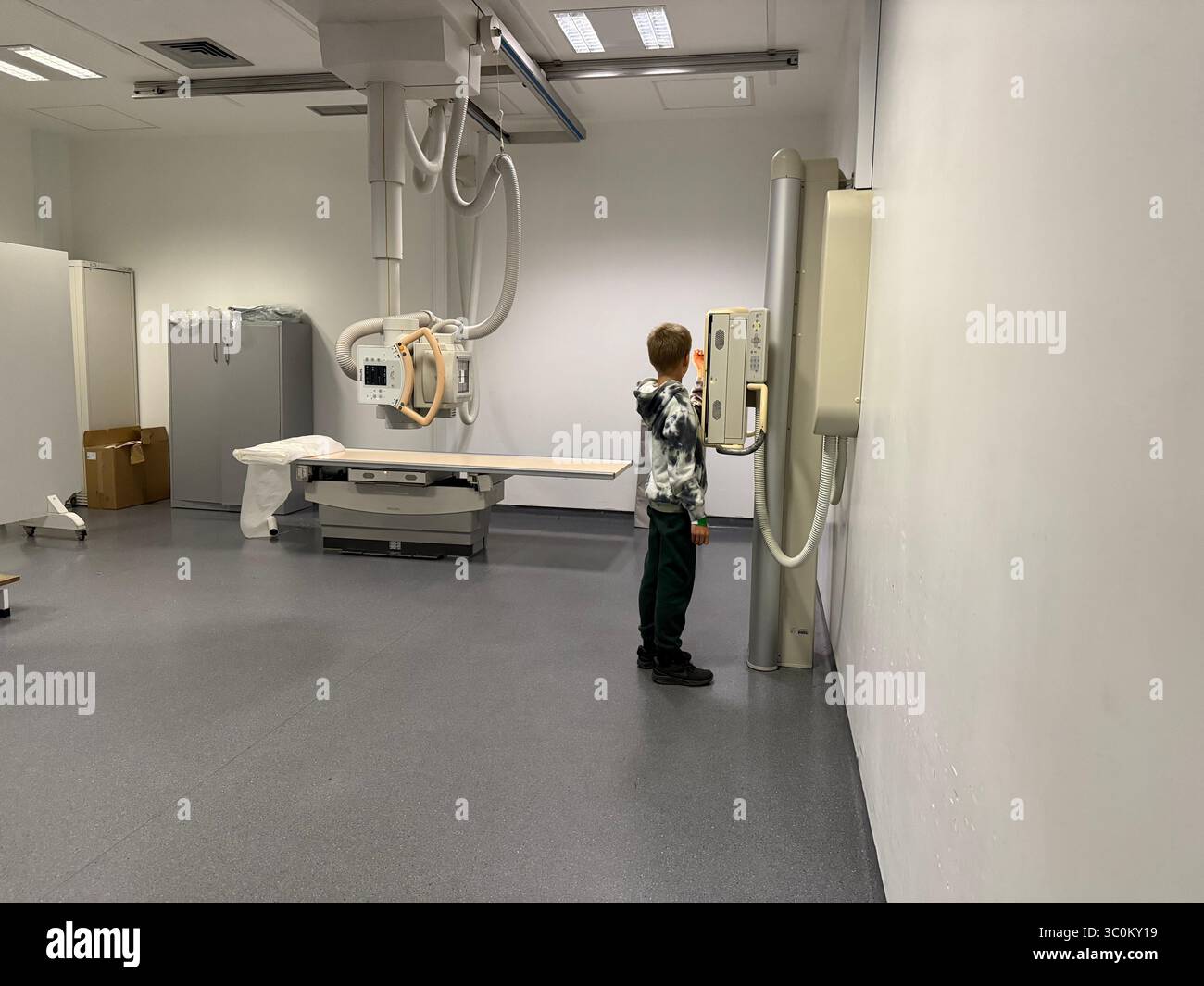 Child standing in X-ray room during radiography exam in medical ...