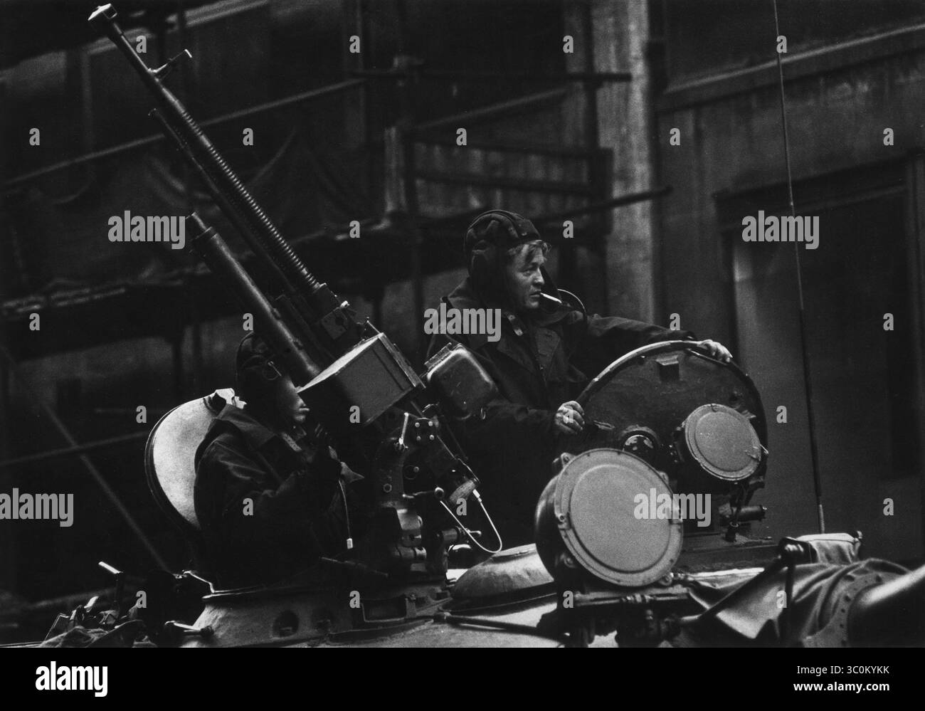 Two Soviet soldiers emerging from the turret of a tank on a side street ...