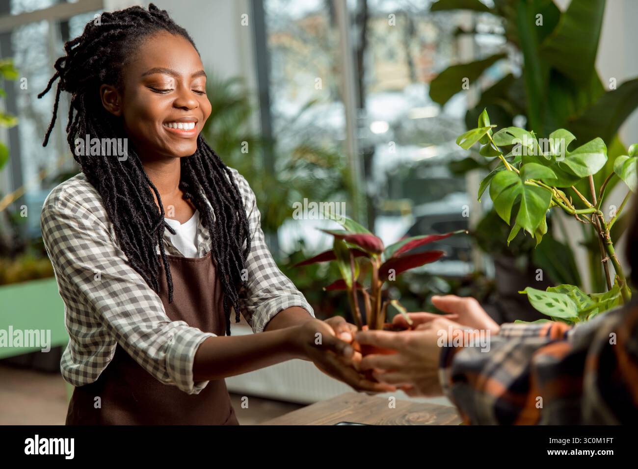 Flower shop assistant selling flower to the customer and smiling nicely ...