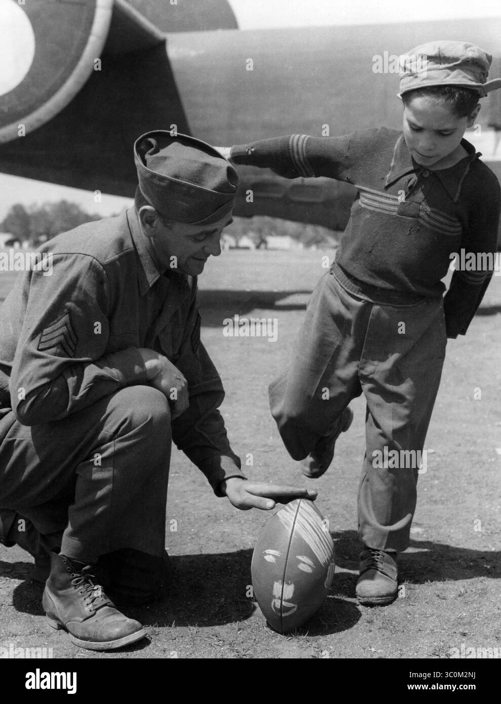 In an Allied Fifteenth Air Force base an American soldier and a child playing with an American ...