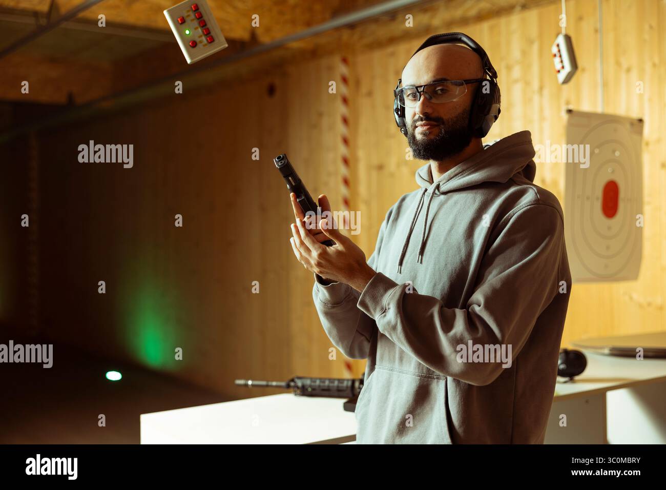 Portrait of Middle Eastern man in indoor shooting range offering rental ...