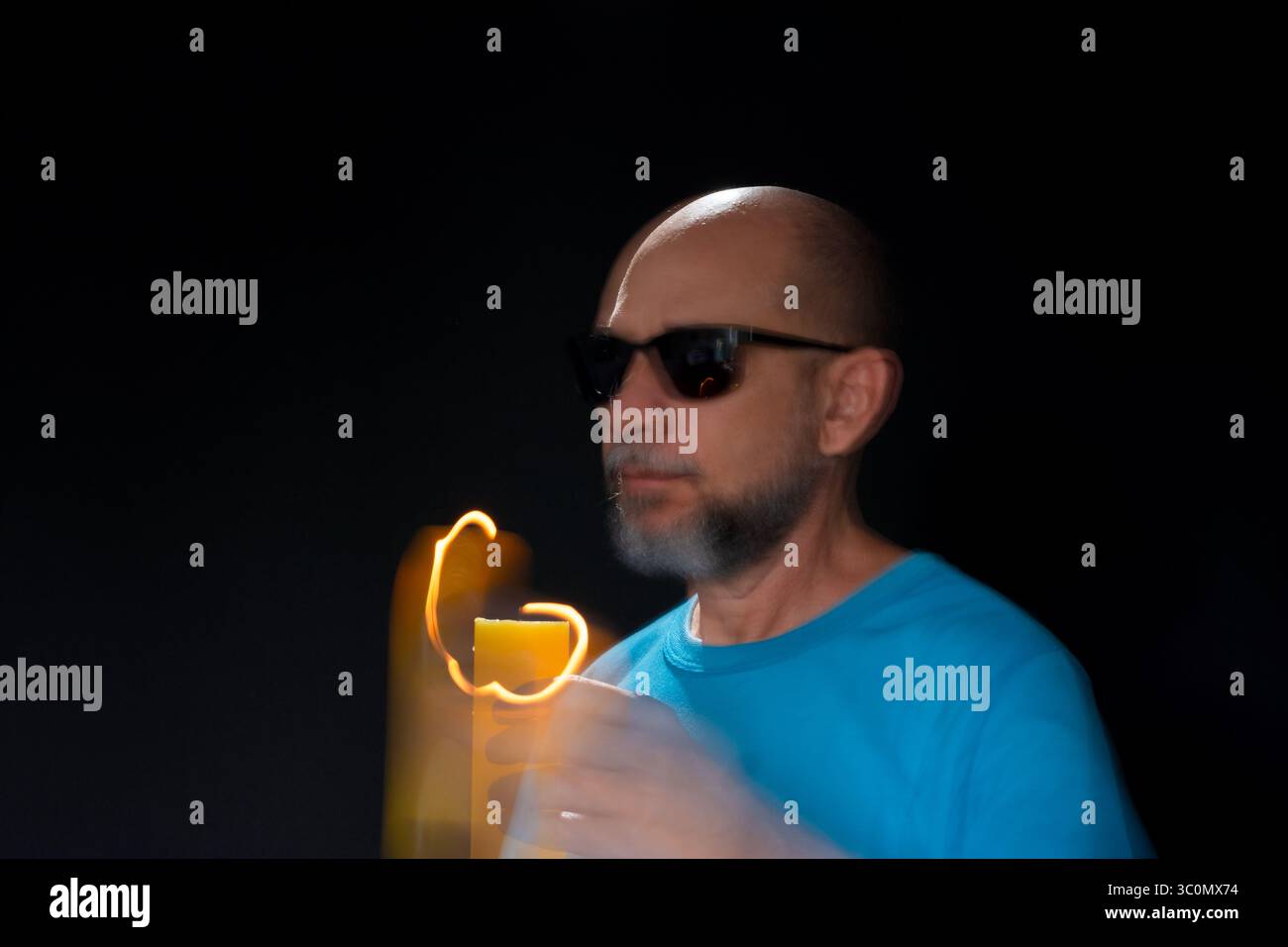 Artistic portrait of bearded bald man in blue shirt making motion blur ...