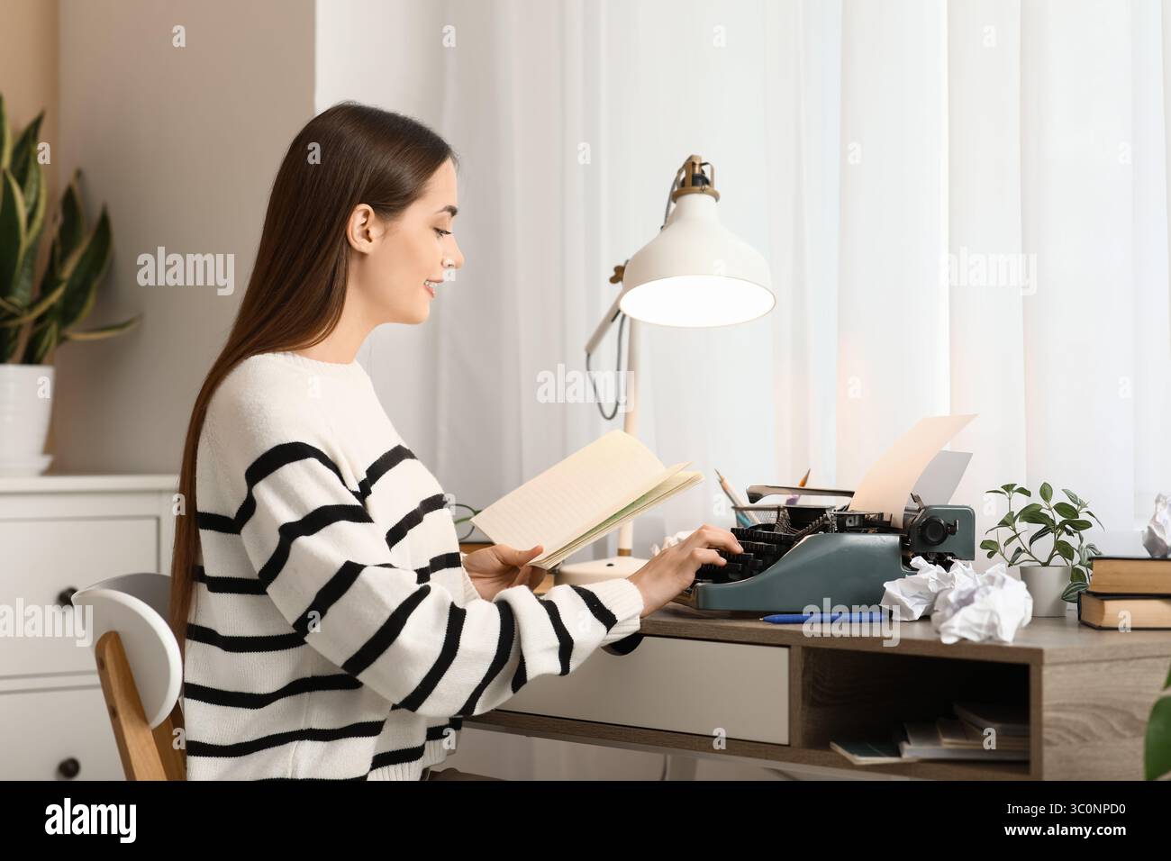 Beautiful happy female writer with typewriter and notebook sitting at ...