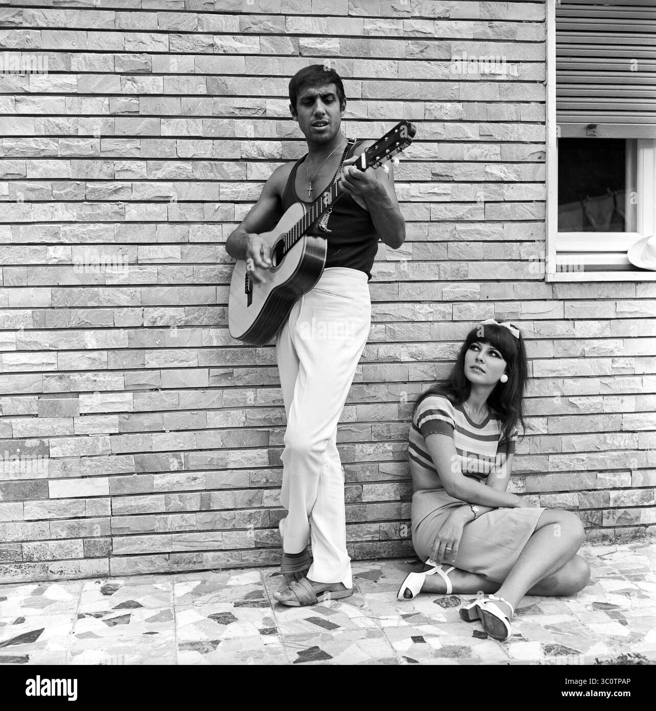 Italian singer and actor Adriano Celentano playing the guitar near his ...