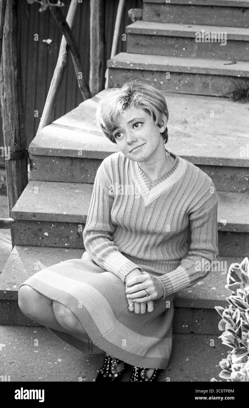 Italian-born Swiss singer and actress Rita Pavone sitting on a step ...