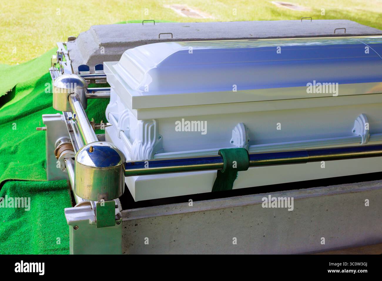 White casket rests on green burial cloth, surrounded by an outdoor ...