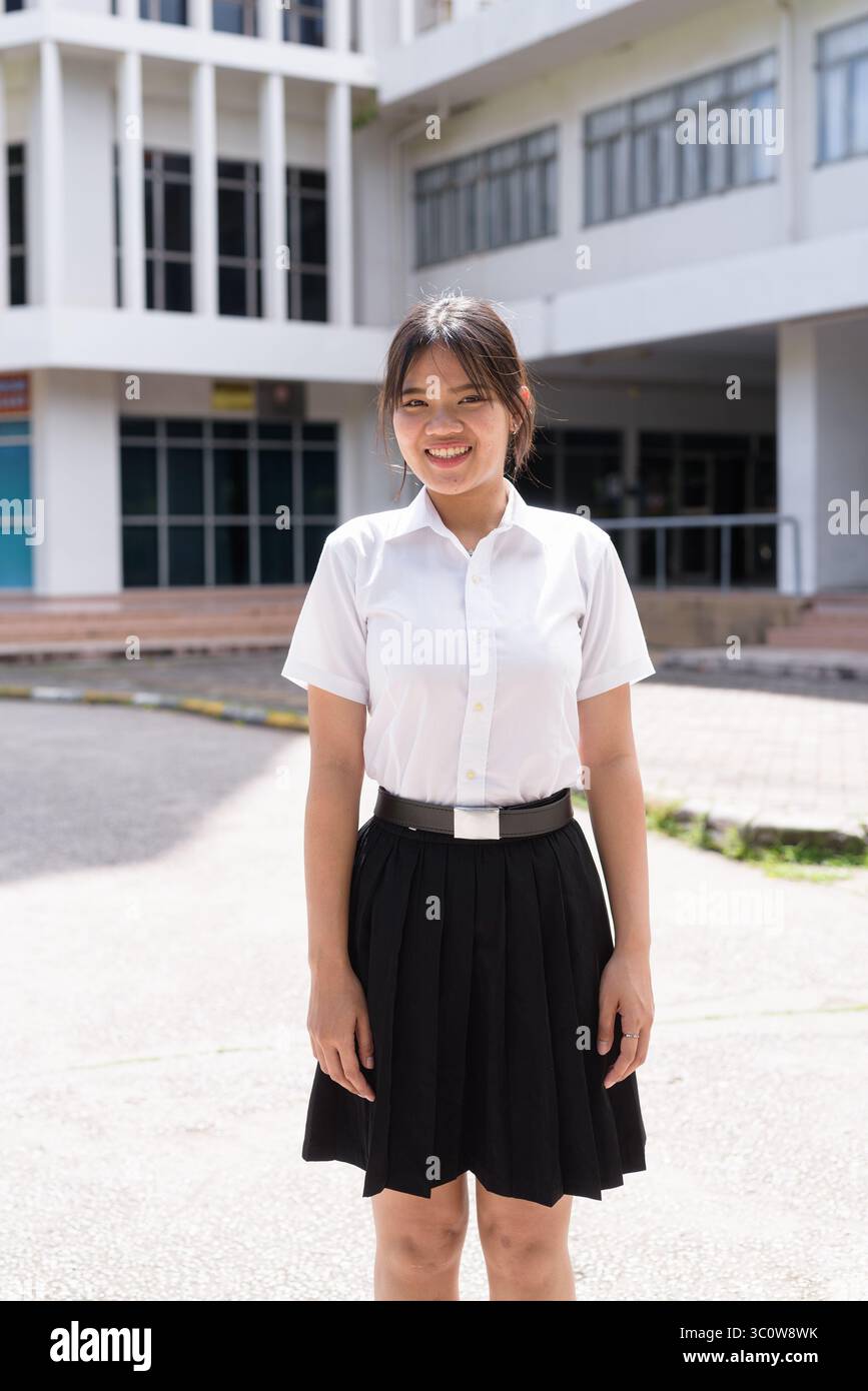 Beautiful Thai university student standing alone on campus grounds ...