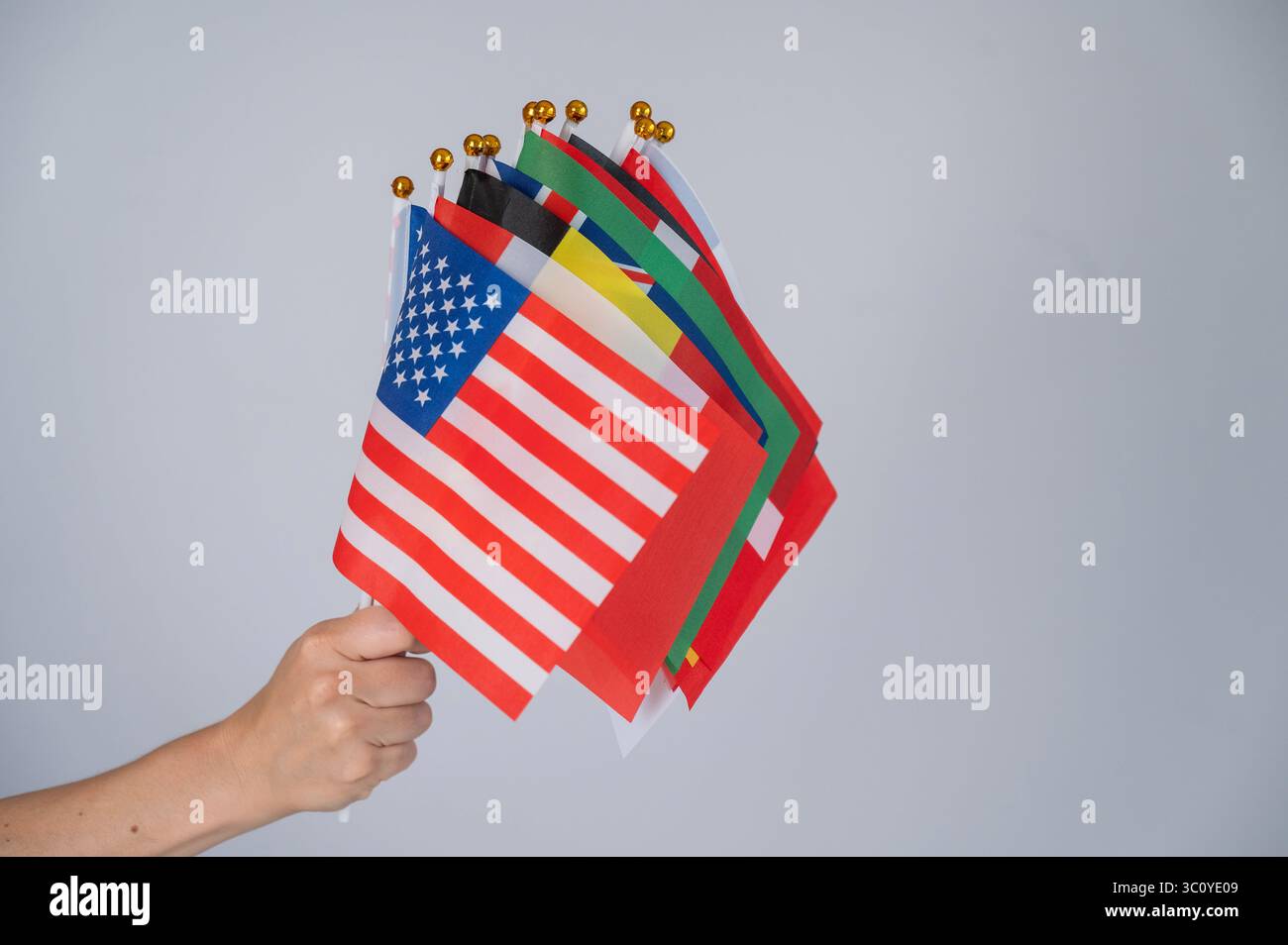A woman's hand holding a bunch of small flags of different countries ...