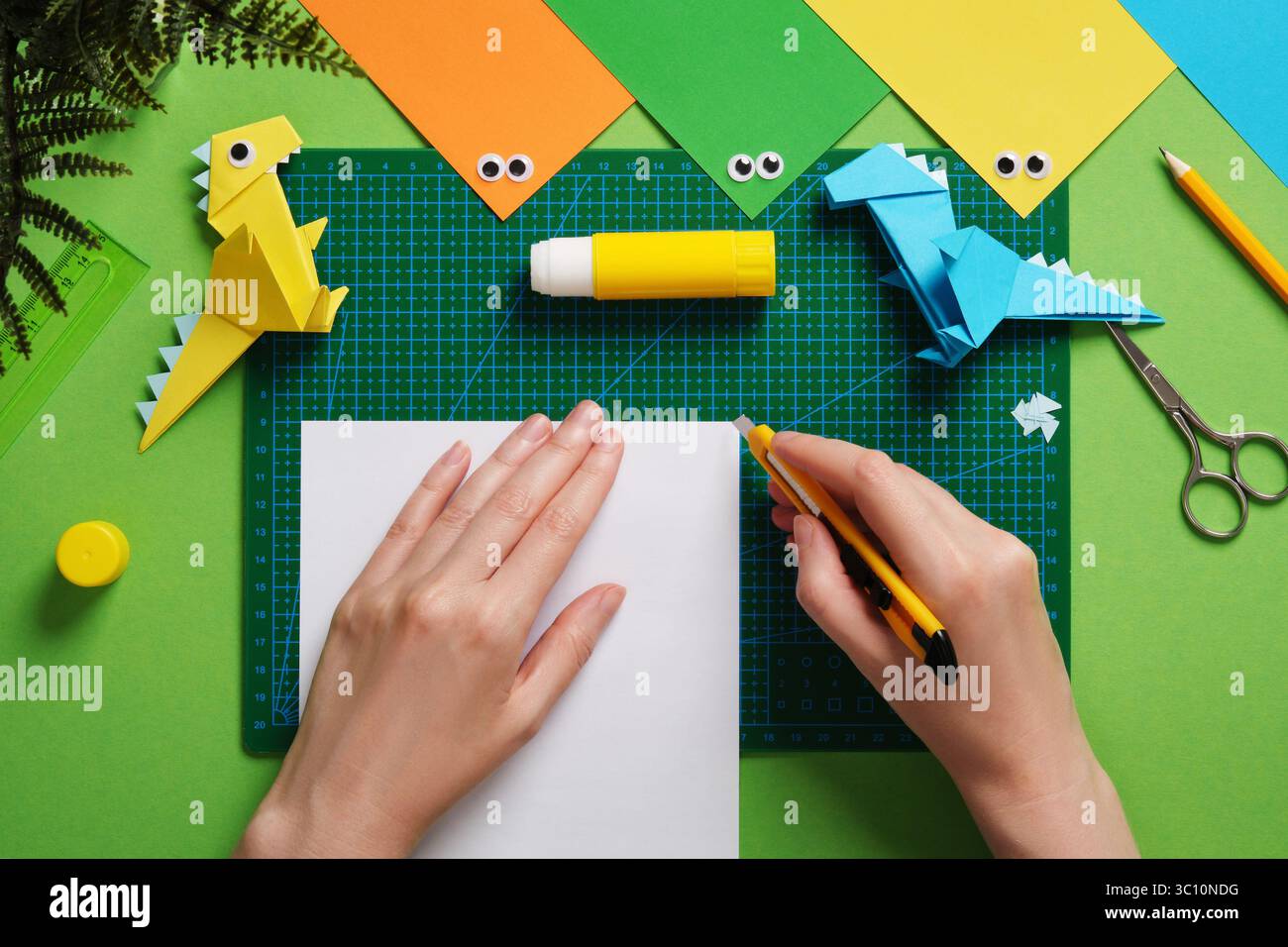 Making an origami dinosaur. Hands cut out the dinosaur's teeth from ...