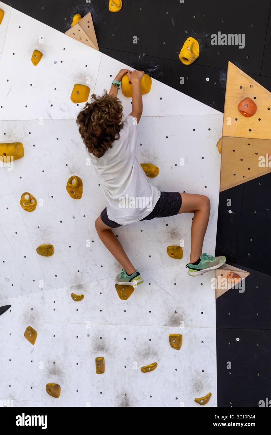 Child practicing bouldering on a climbing wall, building strength and ...