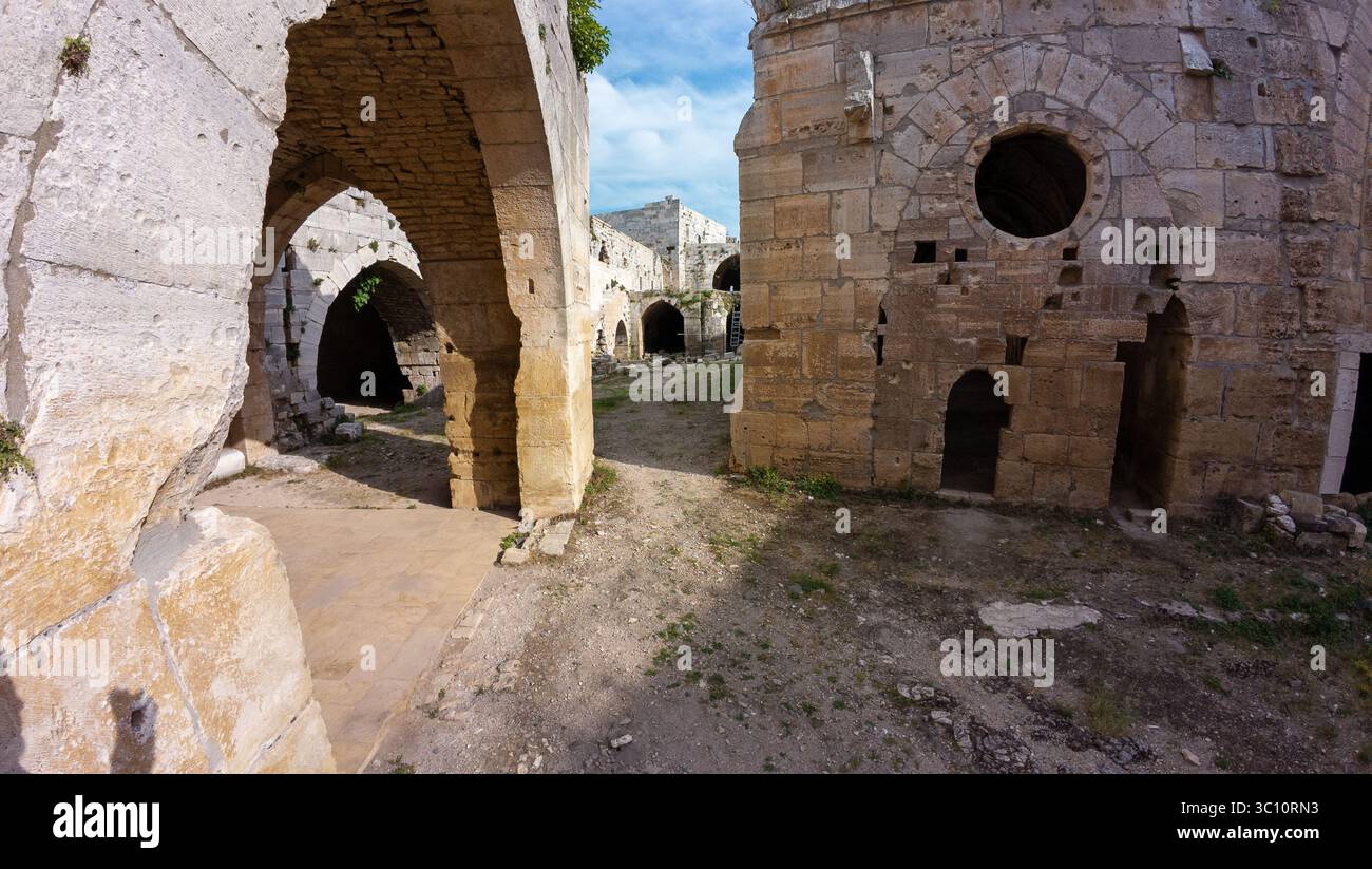 Ancient stone ruins with arches and circular windows under a blue sky ...