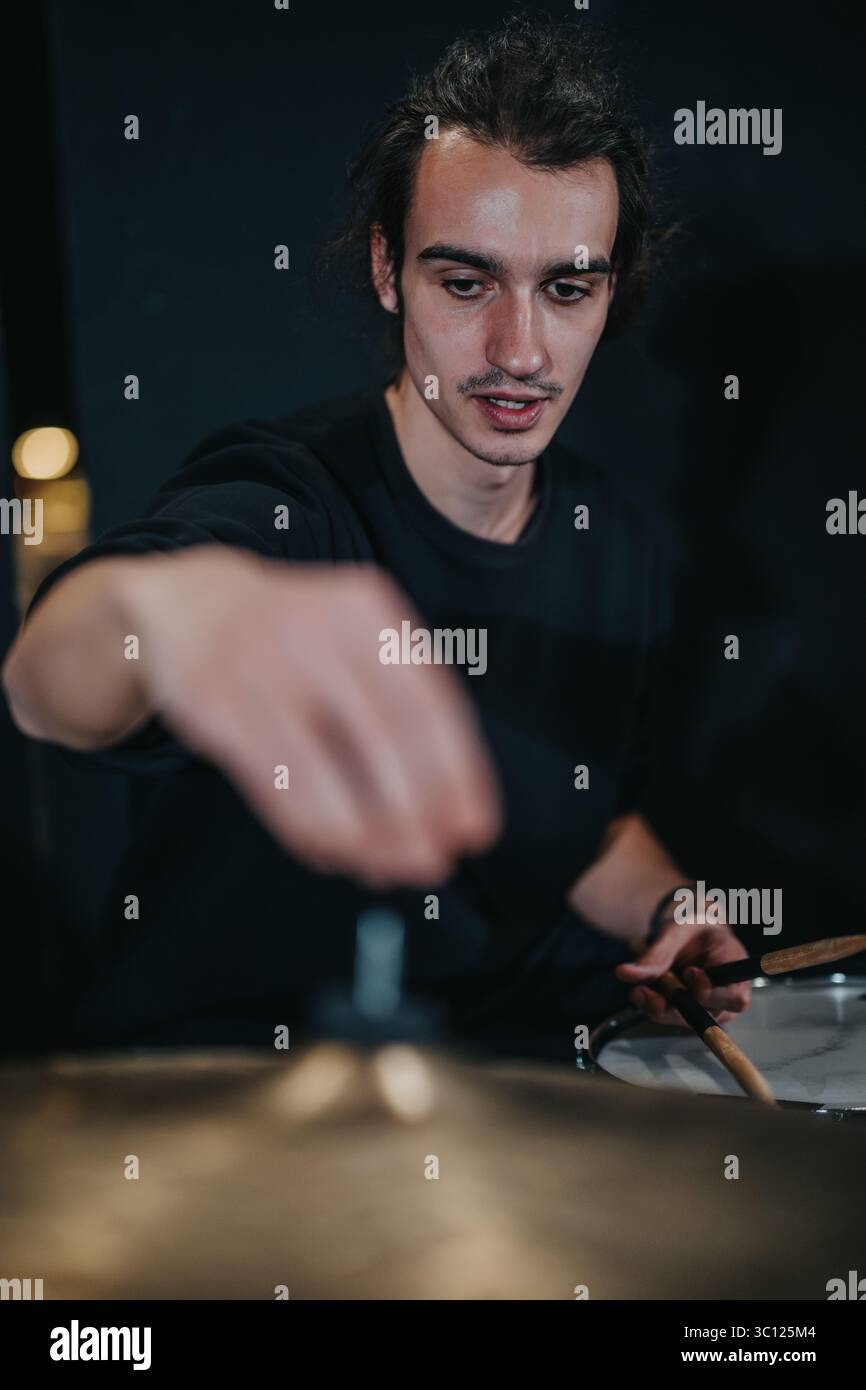 Focused musician adjusting drum set during band practice Stock Photo ...