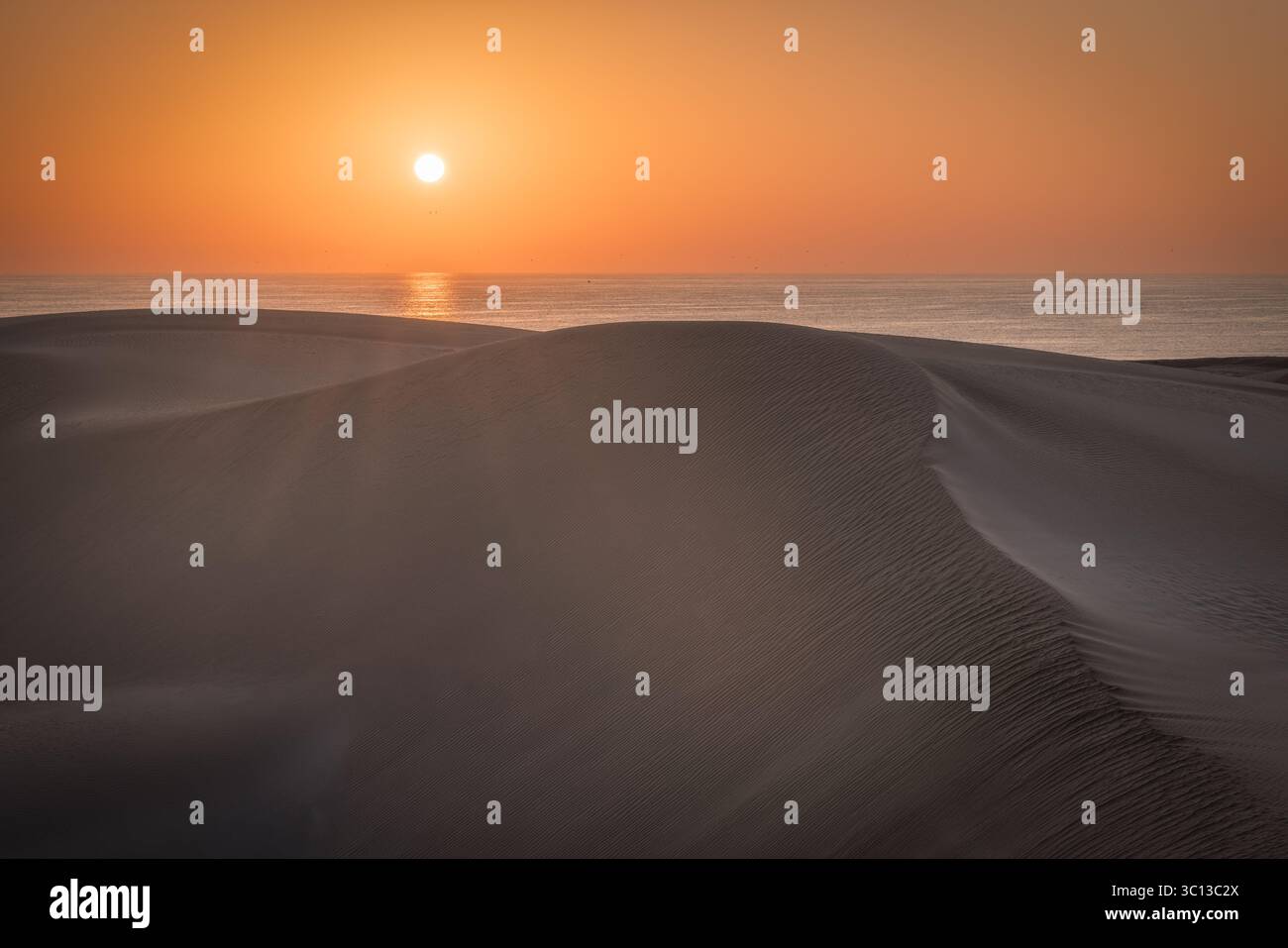 Aerial view of the sun setting over the horizon, casting a warm glow on ...