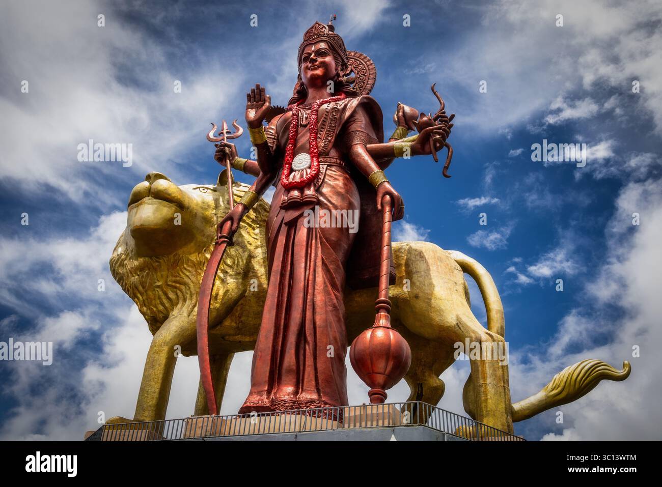 View of a copper-colored Durga statue stands tall upon a golden lion ...