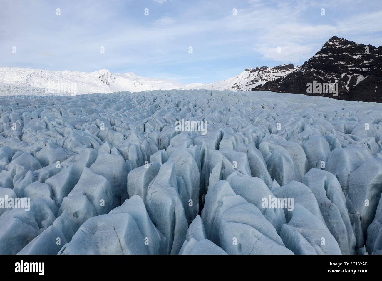 Aerial view of a vast, textured glacial expanse under a blue sky ...