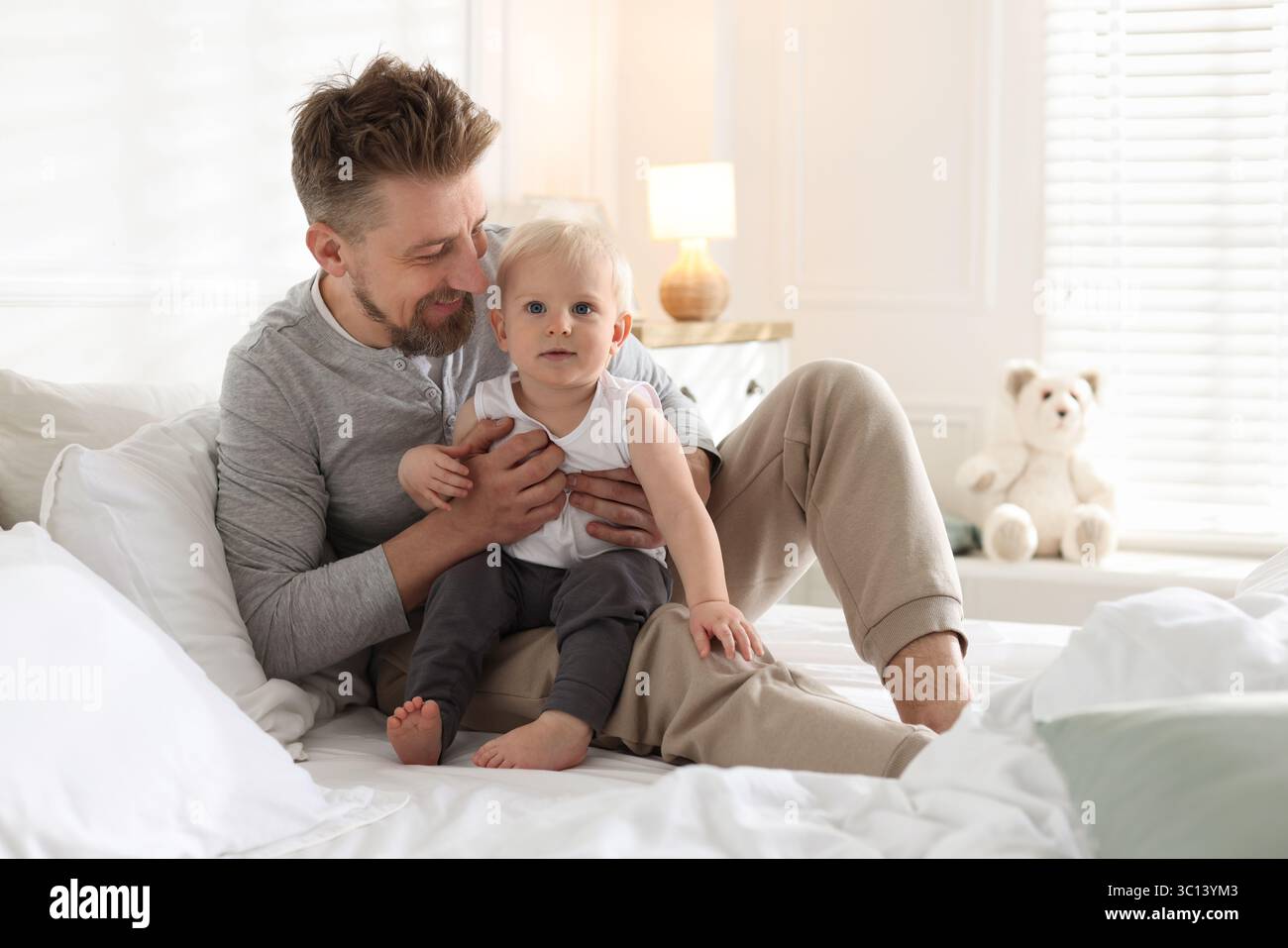 Bedtime. Happy father with his cute little baby on bed at home Stock ...