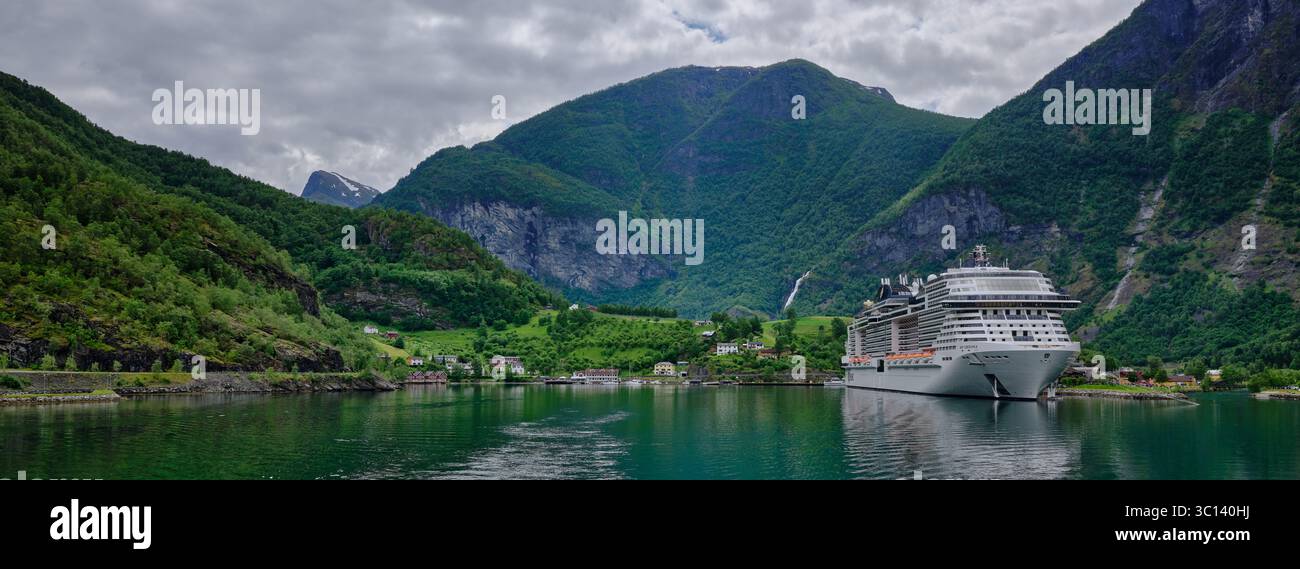 Cruise ship docked at Flåm port, surrounded by steep green mountains ...
