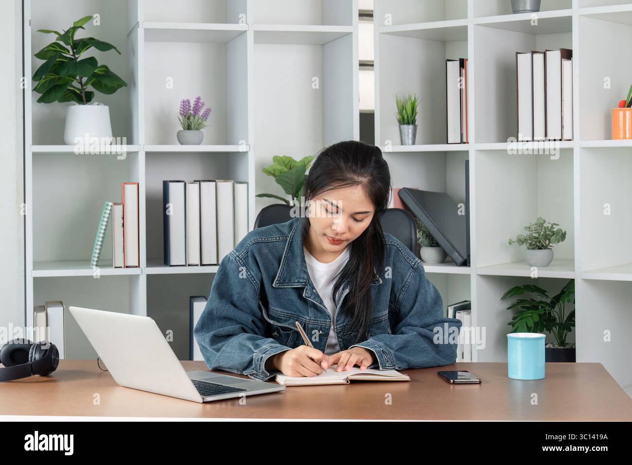 Focused Young Woman Studying at Home with Laptop and Books in a Modern ...