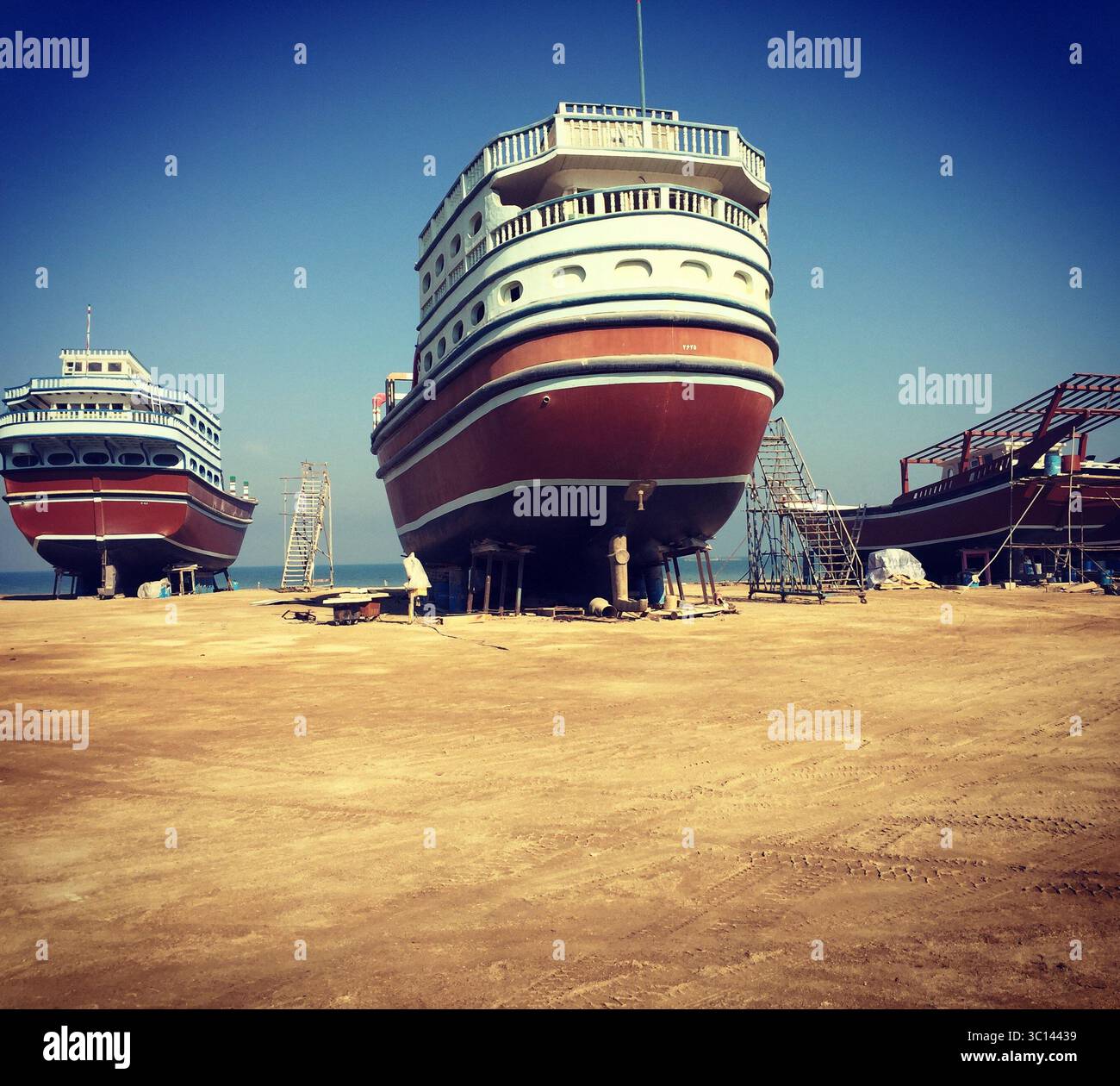 Traditional wooden dhow boats under repair on the Persian Gulf coast ...