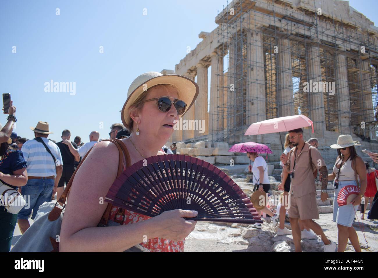 Athens, Greece, 22 July 2025. A visitor waves a hand fan to deal with ...