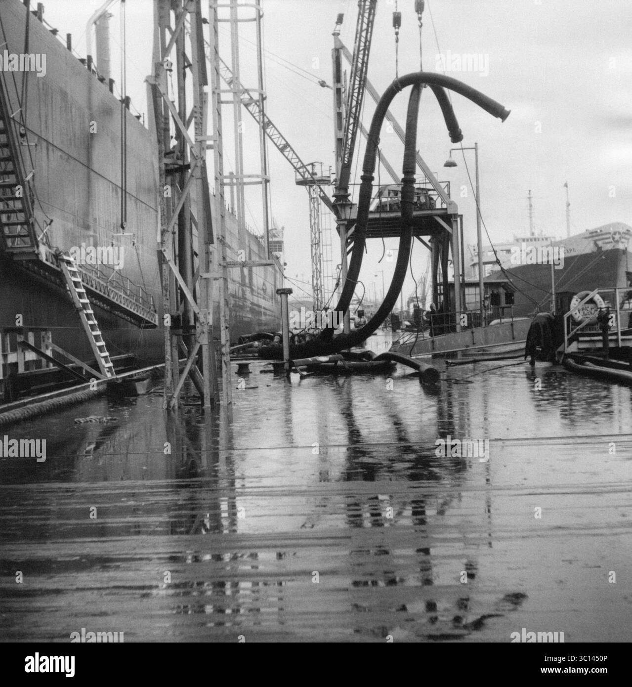 Pipes to channel oil are lifted up on pulleys between the oil tanker ...