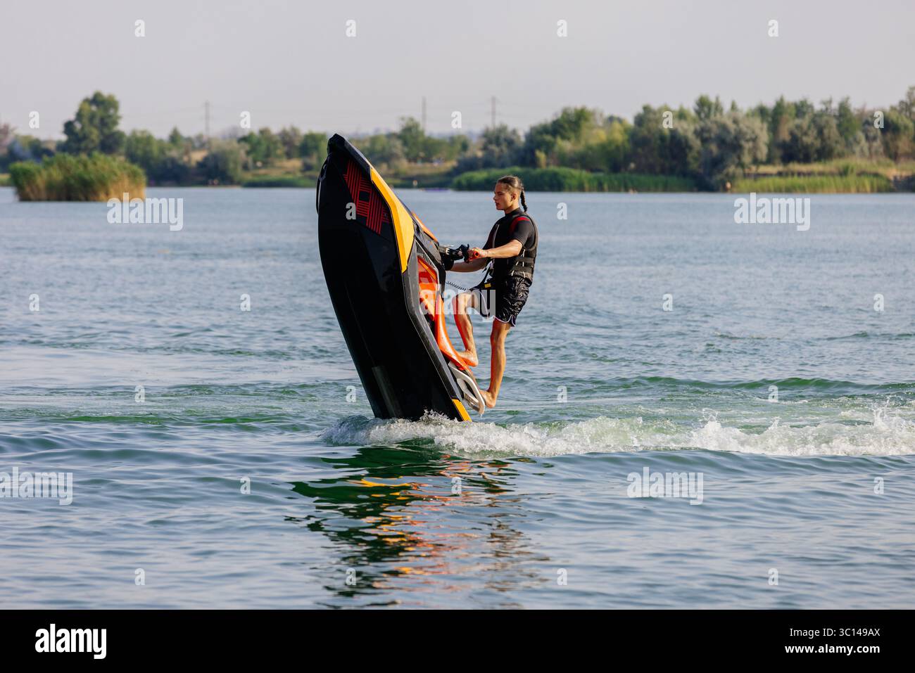 Man riding a jet ski across the water, creating splashes as he speeds over the surface Stock ...