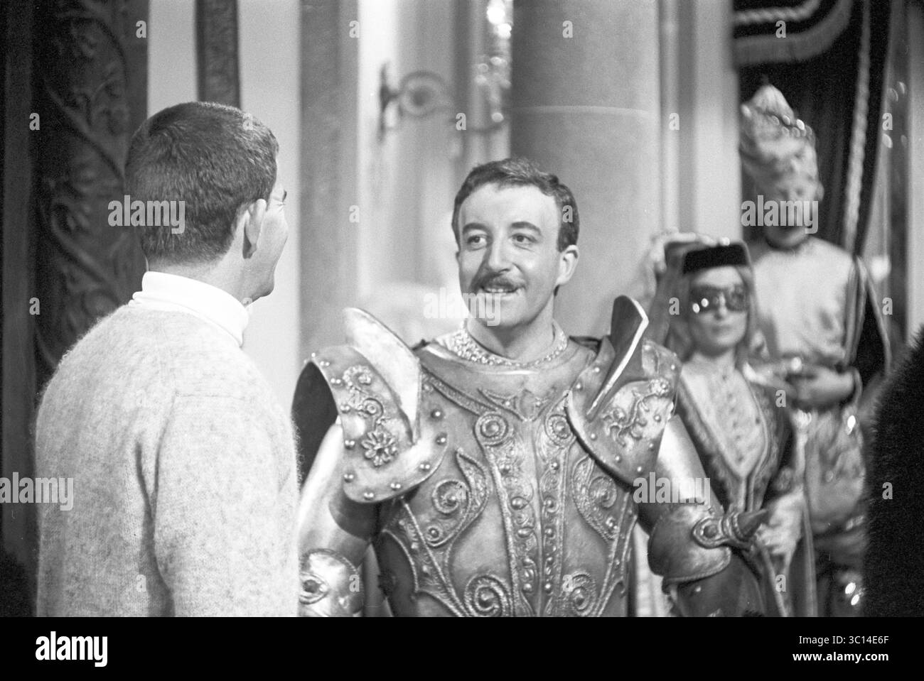 British actor Peter Sellers wearing an armour and discussing with the ...