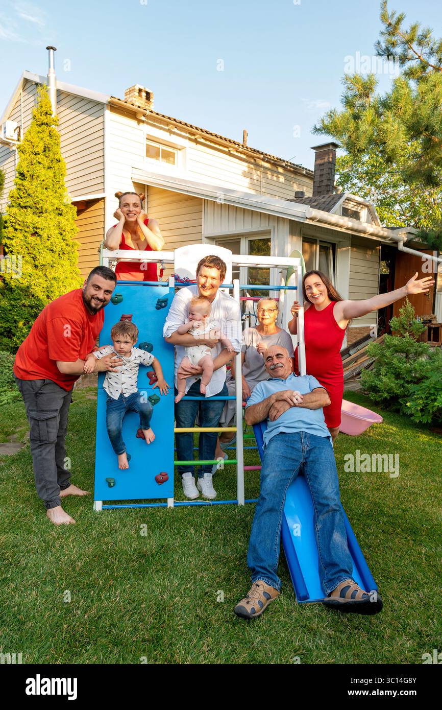 Multi-generational family happily poses around colorful playground ...