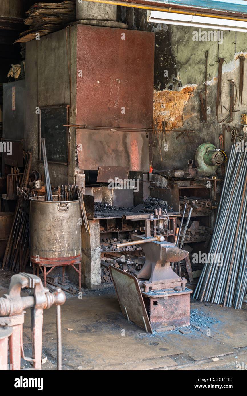 A traditional blacksmith shop forging metal rods by hand using a ...