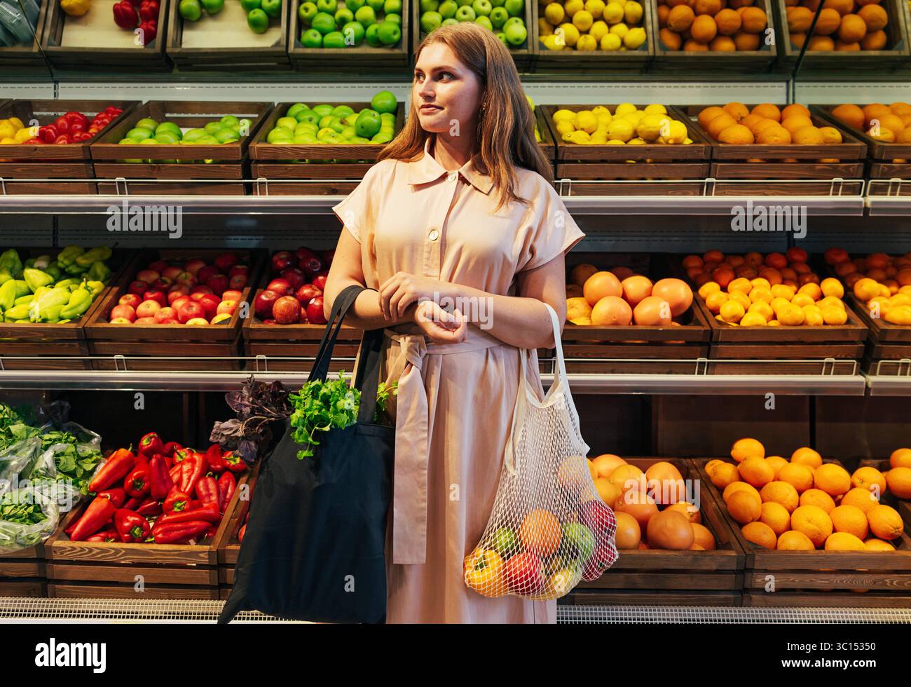 Female customer with bags full of vegetables and fruits standing in ...