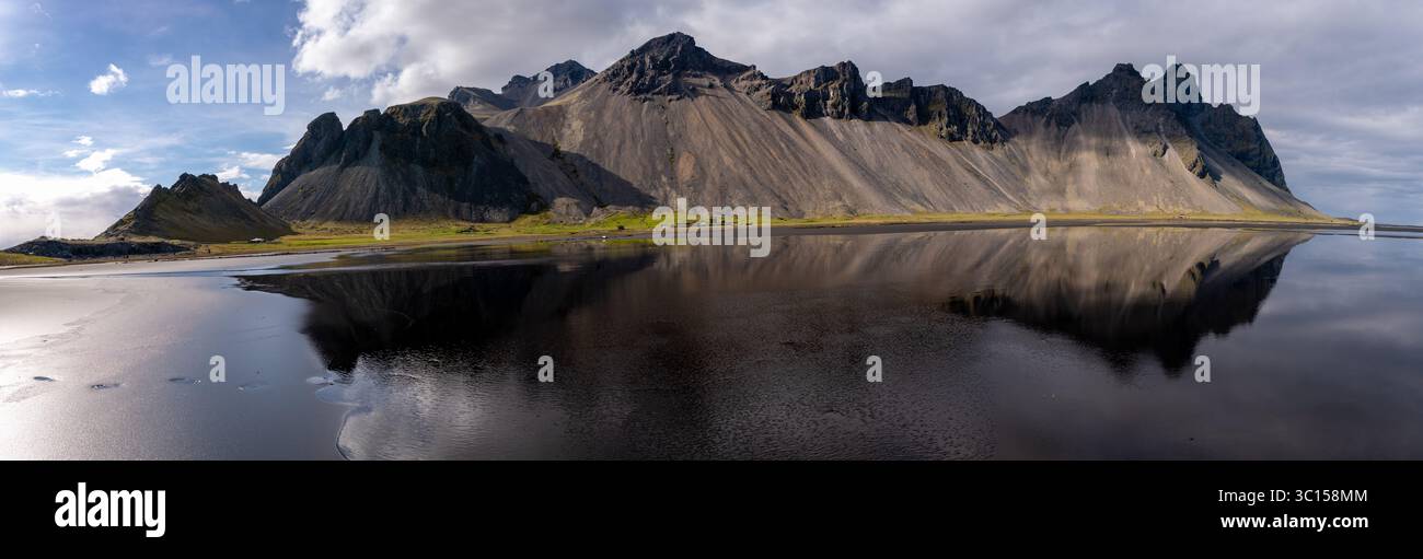 Vestrahorn mountain stands tall in Iceland, its rugged peaks mirrored ...