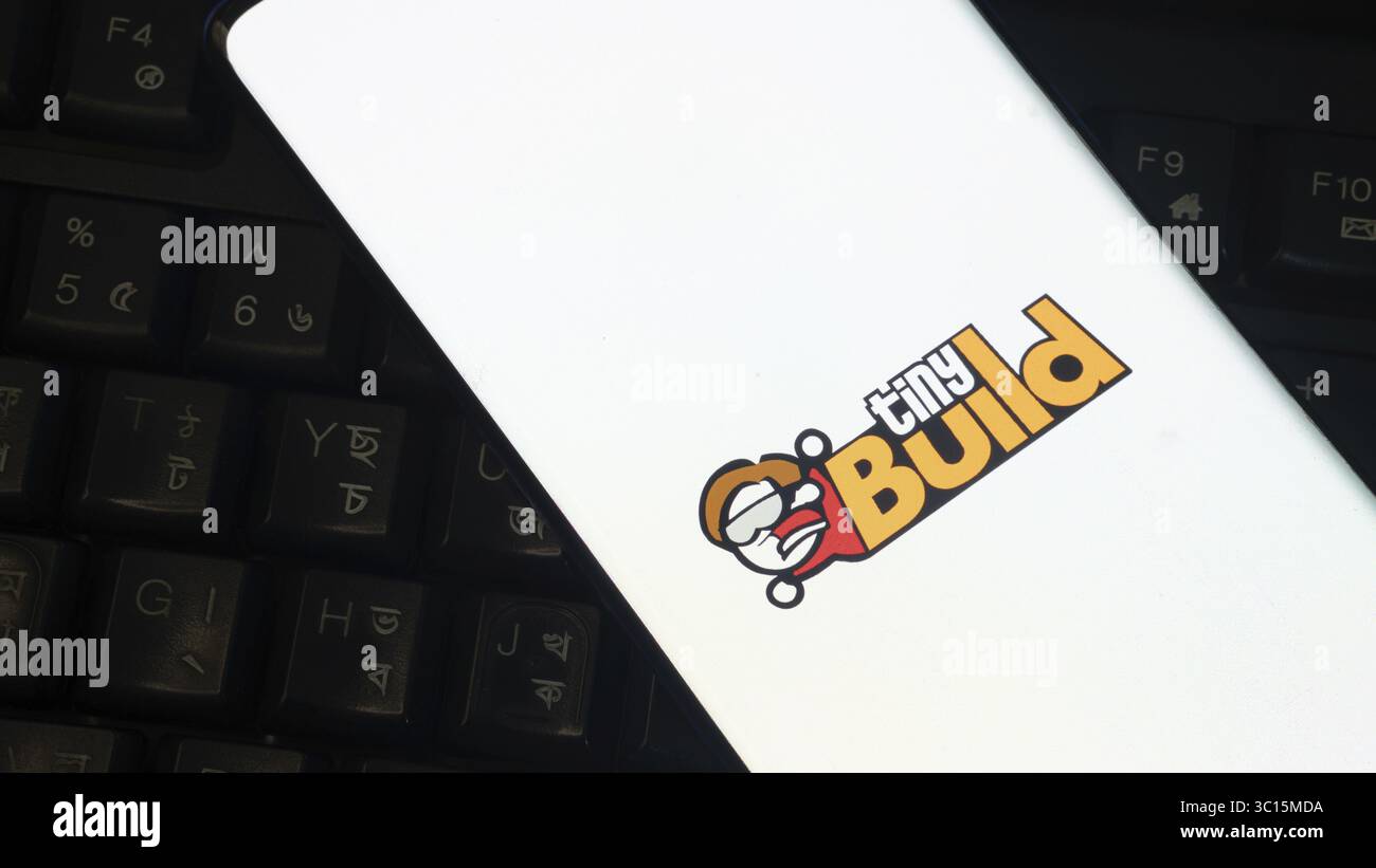 A smartphone showing the tinyBuild logo on a white background, lying on ...
