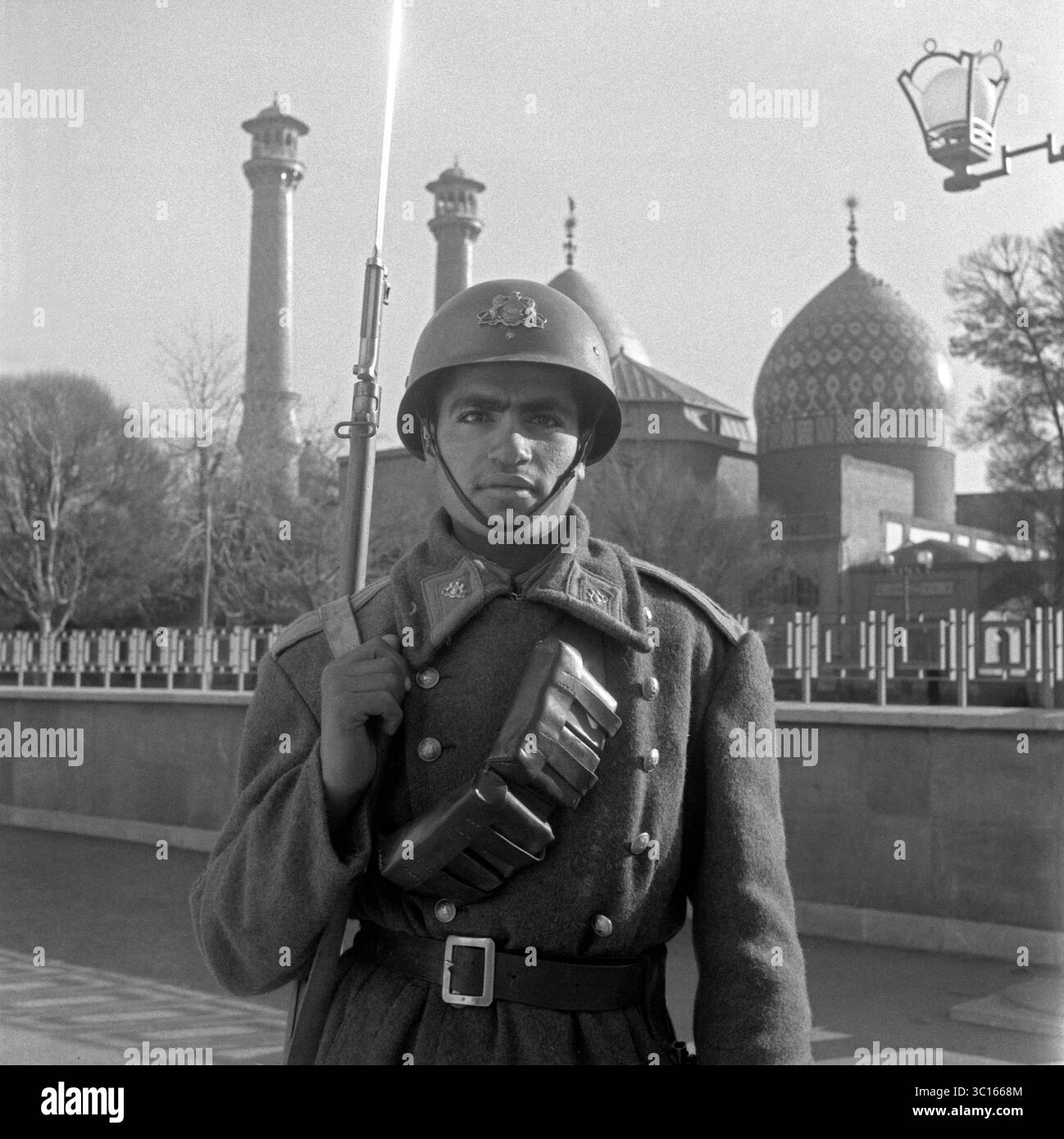A sentry posing wearing weapons and a helmet bearing the symbol of the ...