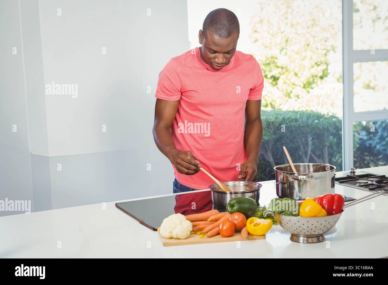 African American man stirring saucepan on induction cooktop at kitchen ...