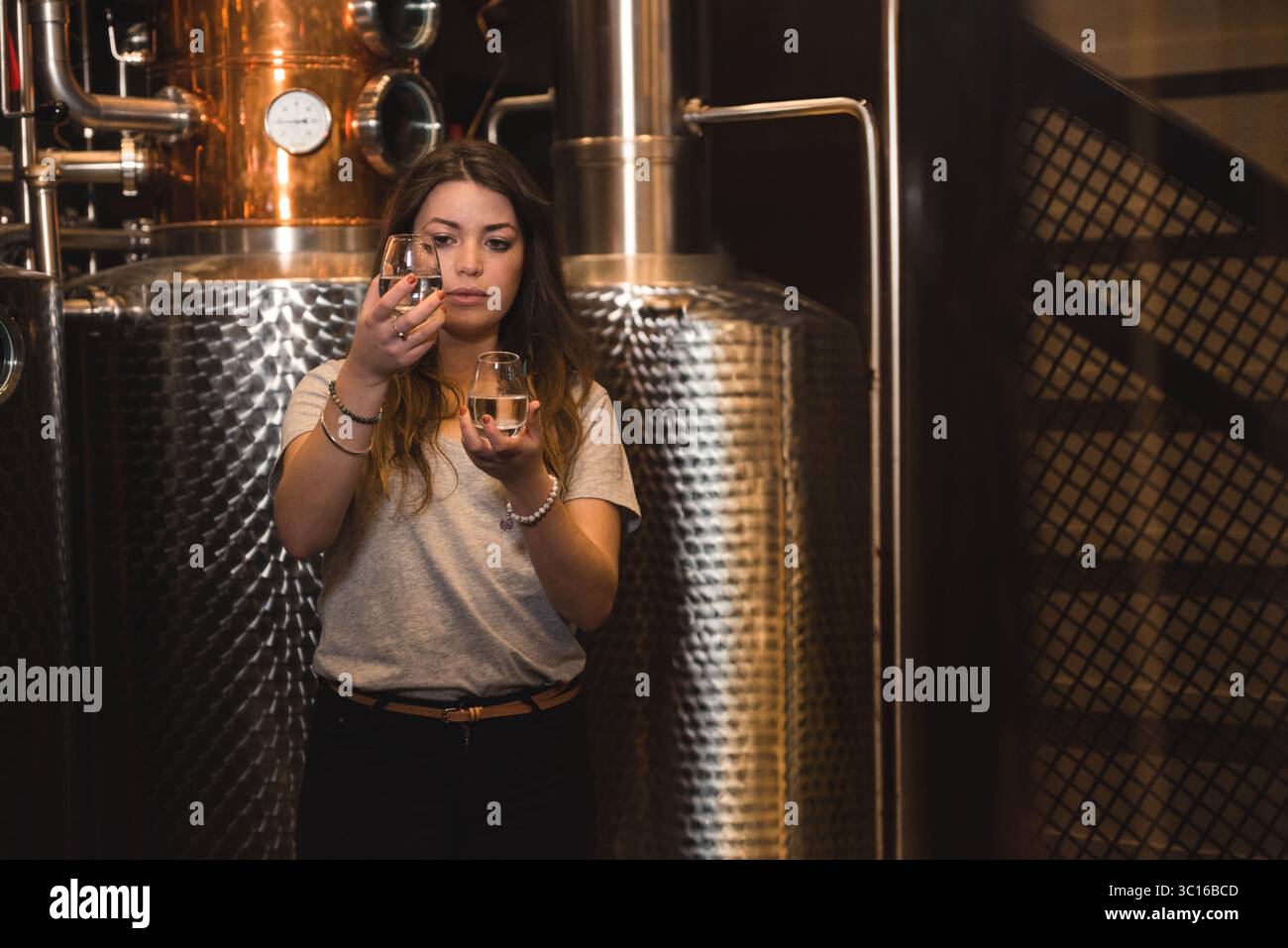 Adult woman technician holding and comparing two spirit samples in ...
