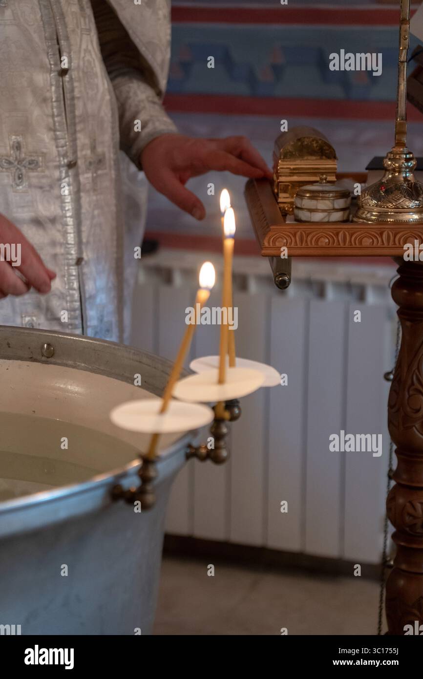 Close-up of a baptismal font filled with holy water and lit ceremonial ...